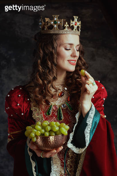 smiling medieval queen in red dress with plate of grapes (1716634773 ...