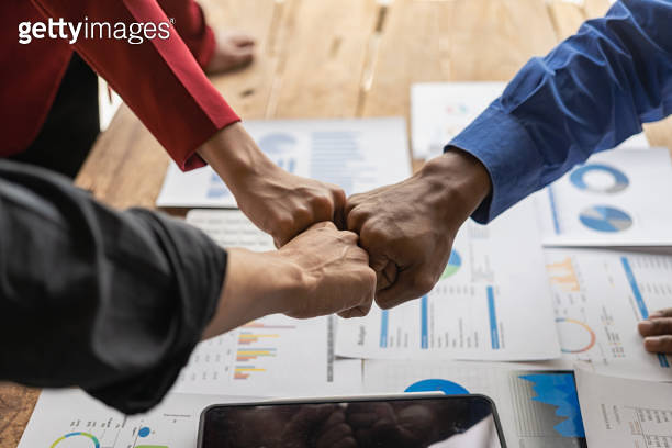 The hands of a team of businessmen joining forces celebrate the concept ...