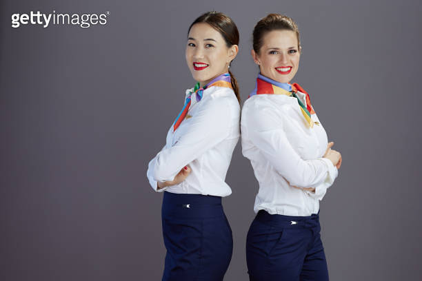 Portrait of happy modern female air hostesses isolated on grey 이미지 ...