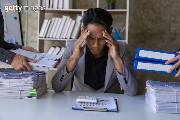 Young accountant stressed out overloaded with paperwork with colleague ...