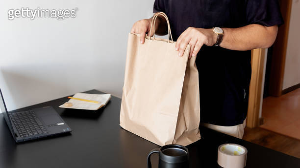 A worker packing a paper bag for shipping 이미지 (1636183400) - 게티이미지뱅크