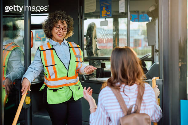 Happy female bus driver talking to a passenger at the station. 이미지 ...