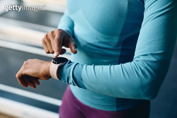 Close up of black athletic woman using smart watch during sports ...