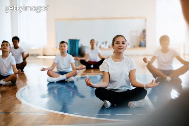 Group of elementary students practicing Yoga during PE class at school ...