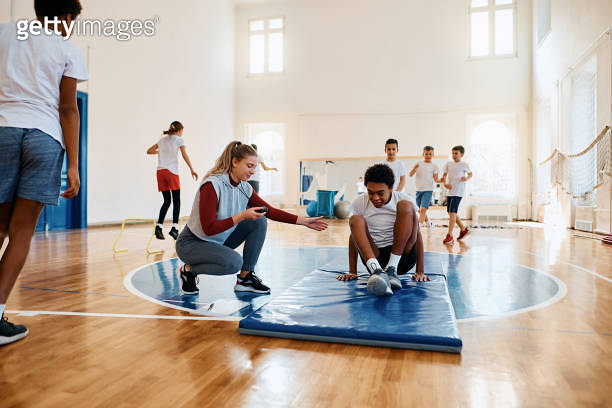 Young female coach and group of kids during exercise class at ...