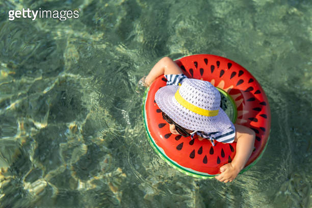 Above view of fashionable young girl in inflatable watermelon float in ...