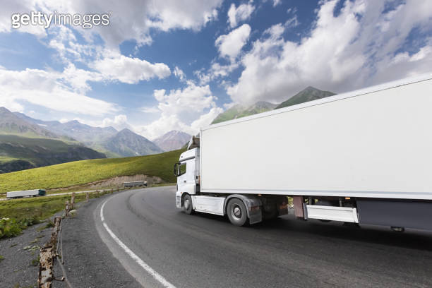 semi truck driving through mountain road pass 이미지 (1746338389) - 게티이미지뱅크