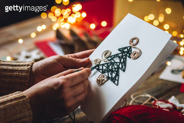 Woman creating handmade craft paper christmas card with wool thread fir ...