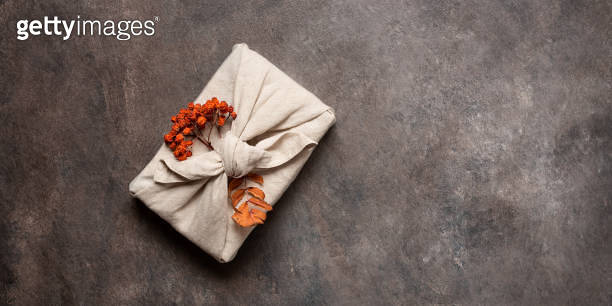 Autumn gift with rowan wrapped in fabric on brown rustic background. A ...