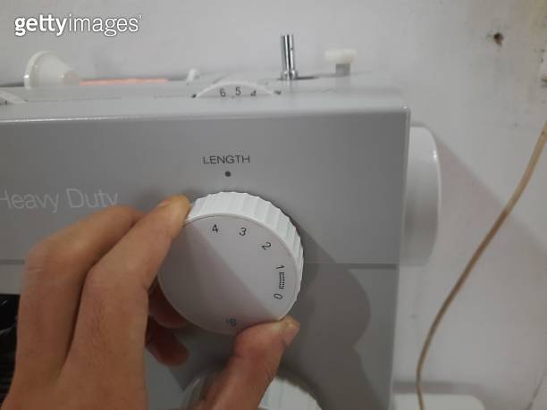 someone's hand adjusting the controls on a portable sewing machine 이미지 ...