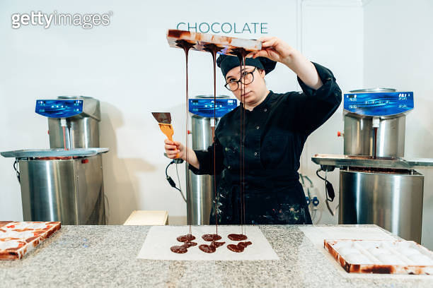 female chocolate master chef in black uniform working in confectionery ...