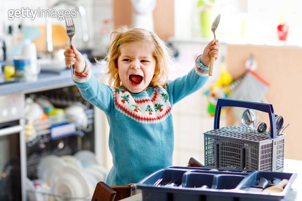 Cute little toddler girl helping in the kitchen with dish washing ...