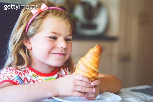 Smiling child at breakfast. Food and happy kids. The girl is eating a ...