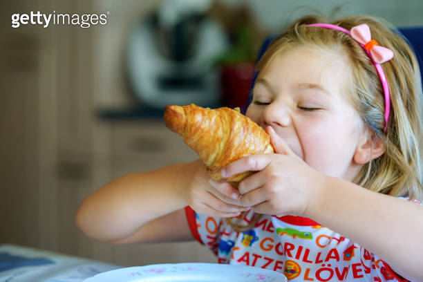 Smiling child at breakfast. Food and happy kids. The girl is eating a ...