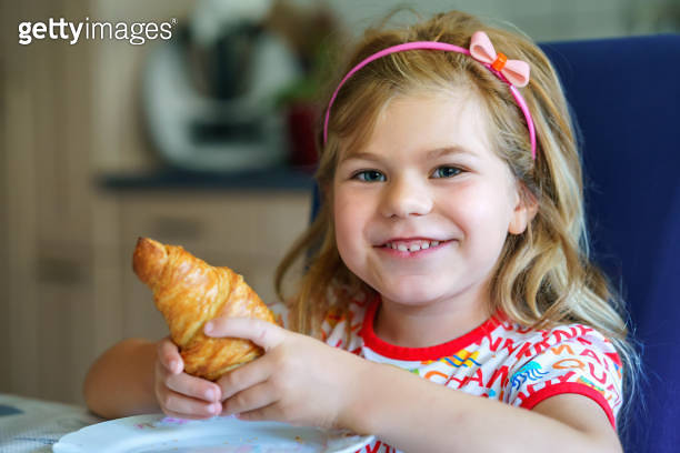 Smiling child at breakfast. Food and happy kids. The girl is eating a ...