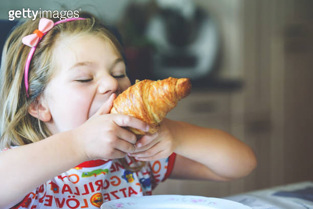 Smiling child at breakfast. Food and happy kids. The girl is eating a ...