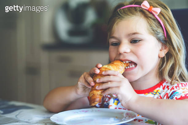 Smiling child at breakfast. Food and happy kids. The girl is eating a ...