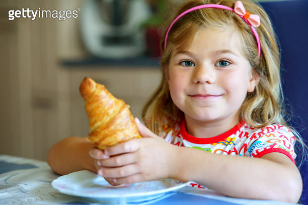 Smiling child at breakfast. Food and happy kids. The girl is eating a ...