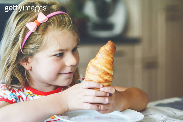 Smiling child at breakfast. Food and happy kids. The girl is eating a ...