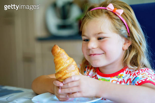 Smiling child at breakfast. Food and happy kids. The girl is eating a ...