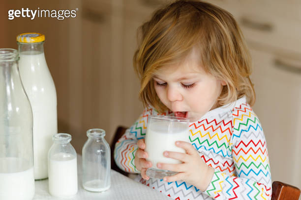 Adorable toddler girl drinking cow milk for breakfast. Cute baby ...