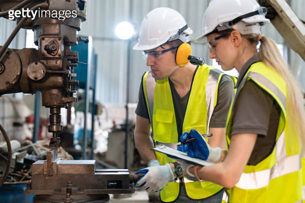 Male and female engineers in safety vest with helmet checking and ...