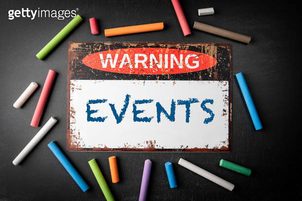 Events. Metal warning sign and colored pieces of chalk on a dark ...
