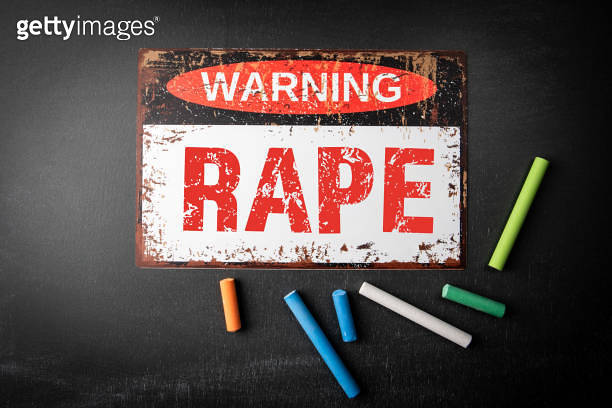 RAPE. Metal warning sign and colored pieces of chalk on a dark ...