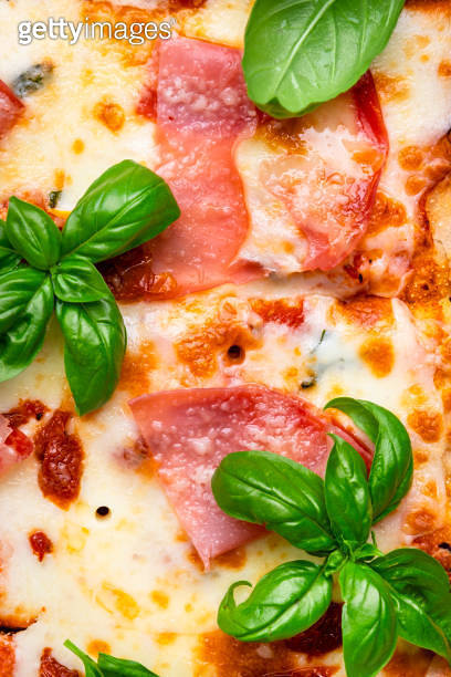 Rectangular hot pizza with ham, cheese, dried tomatoes, spicy sauce and ...