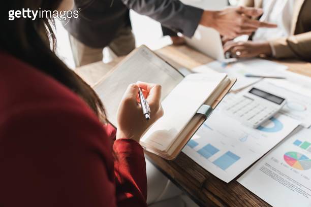 Cheerful business taking notes during meeting for discussing working ...