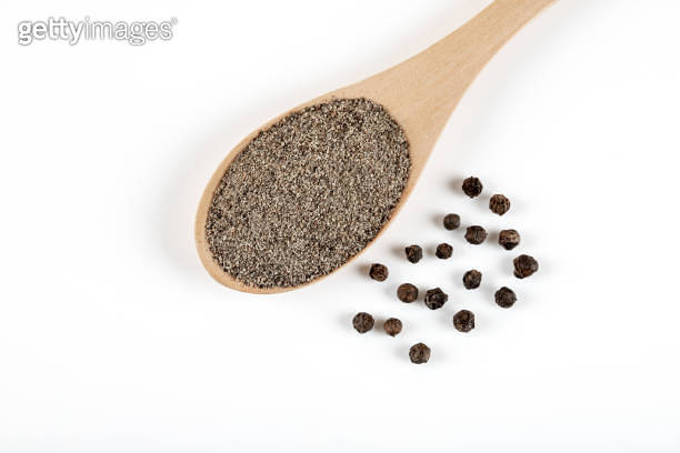 Ground black pepper with grains of black pepper on a white background ...