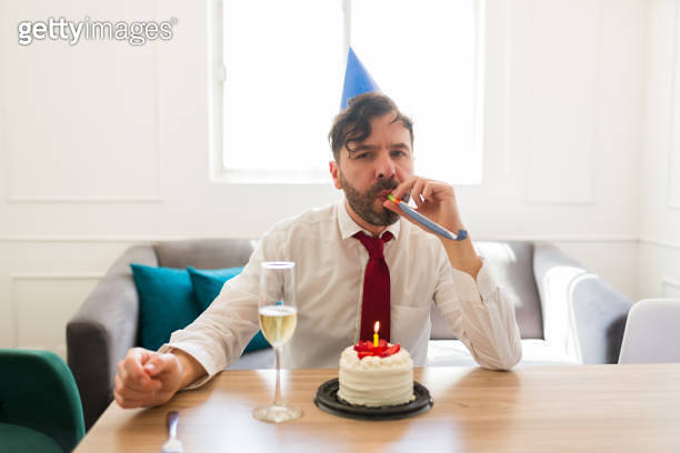 Depressed man celebrating his sad birthday alone 이미지 (1708561538) - 게티이미지뱅크