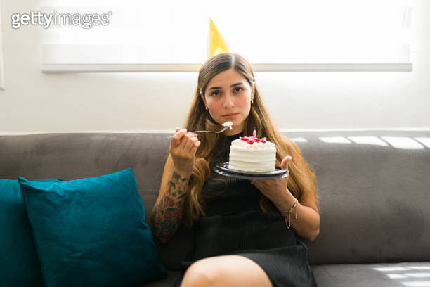Sad young woman eating her birthday cake alone 이미지 (1708551644) - 게티이미지뱅크
