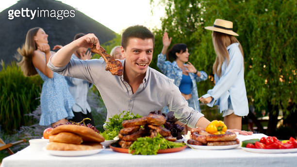 Outdoor dining table with delicious BBQ meats, fresh vegetables and ...