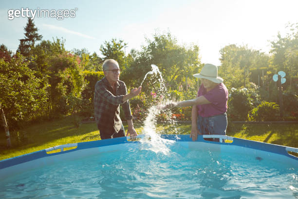 Senior couple splashing water on each other while enjoying in garden ...
