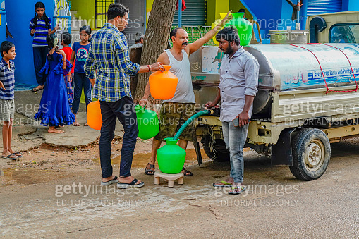 Three men take drinking water from a mobile water tank in Puttaparthi ...