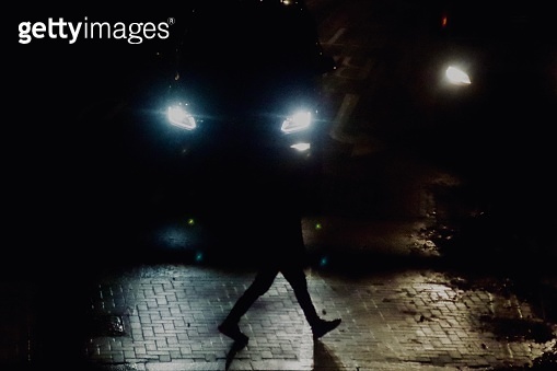 People crossing the road at night lit up by car headlights. 이미지 ...