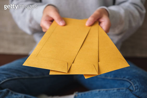 Closeup image of a woman holding and giving brown envelopes 이미지 ...