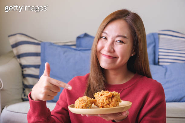 Portrait image of a woman holding and pointing finger at a plate of ...