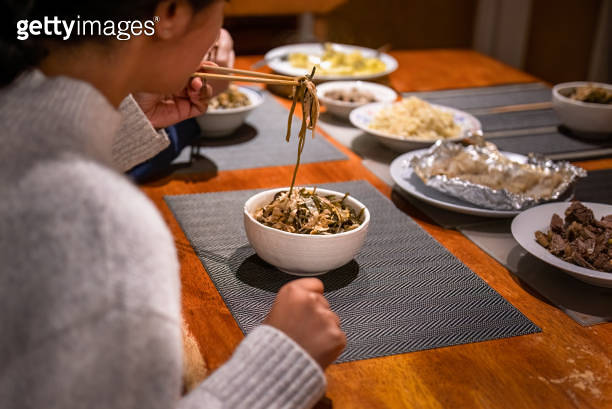 Left-handed woman holding chopsticks and eating dinner. Vegetable and ...