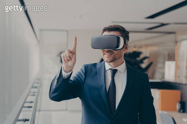 Smiling suited employee in AR/VR glasses, interacting with virtual ...