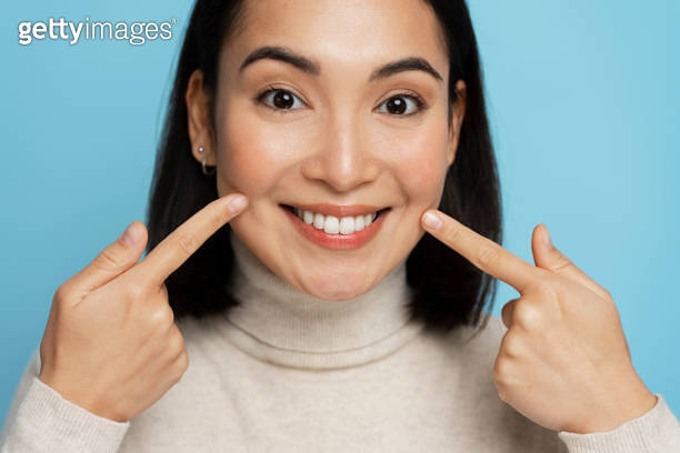 Portrait of pretty cheerful woman points index fingers at smile shows ...