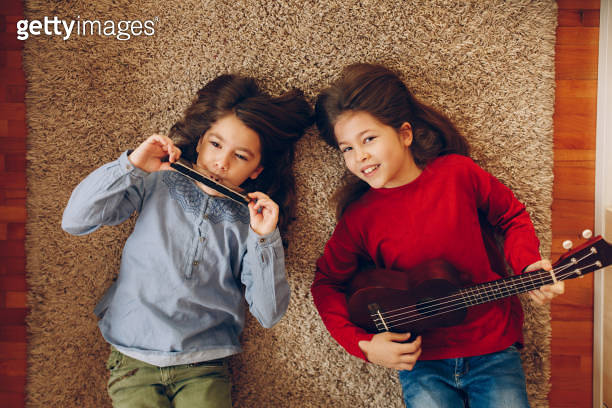 Cheerful teenage girls playing on a musical instruments and having fun ...