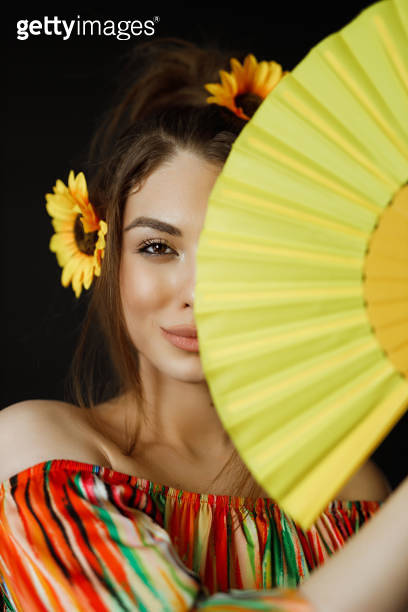 Playful young woman with sunflowers and a yellow hand fan 이미지 ...
