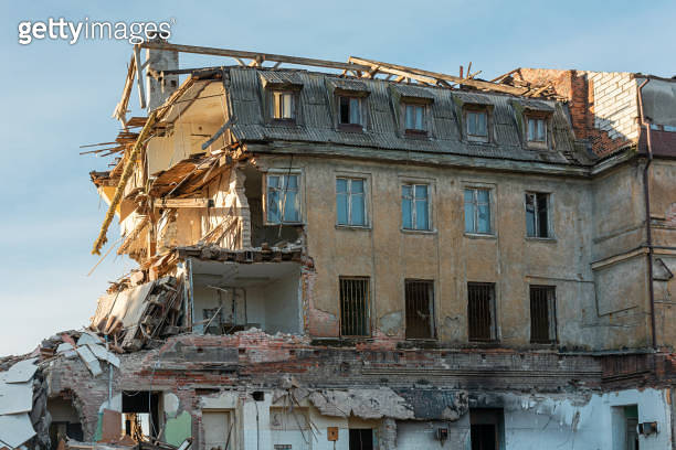 A large destroyed building with broken apartments and a pile of ...