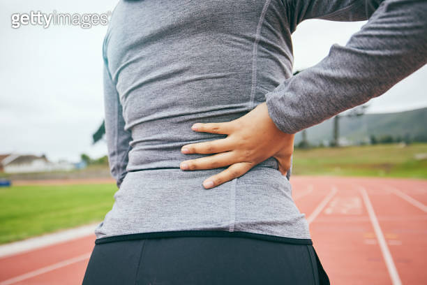 Hand, back pain and fitness with a sports person outdoor on a track ...
