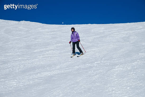 Enjoying skiing in ski-wear down the slope covered in white snow on a ...