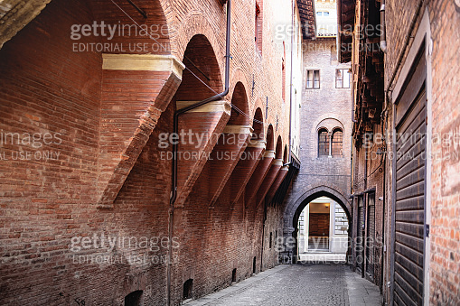 Alley between old fashioned brick buildings with arch in the end in ...