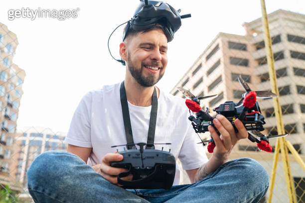Portrait of smiling pilot man wearing goggles and holding remote ...