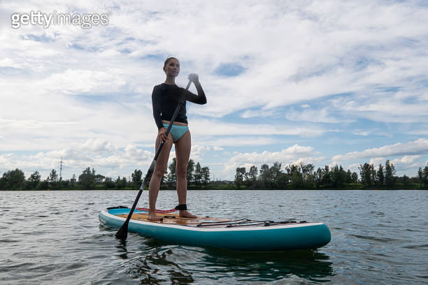 woman in a blue swimsuit stands on a spa board with a paddle on the ...